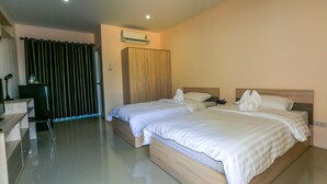 Quarto de hotel com duas camas, uma escrivaninha, uma cadeira e um ar condicionado.