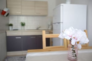 Cozinha com armários de madeira, uma geladeira e um vaso com flores brancas sobre uma mesa.