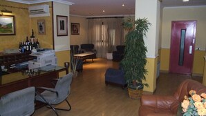 Um saguão de hotel com balcão de recepção, área de estar e uma porta.
