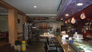 Interior de restaurante com balcão, área de estar e vitrine com alimentos.