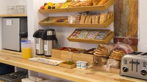 Um balcão de café da manhã com diversos alimentos, uma cafeteira e uma torradeira.