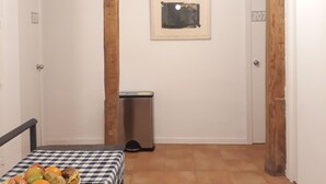 Um corredor com toalha xadrez, uma lixeira e um quadro na parede.