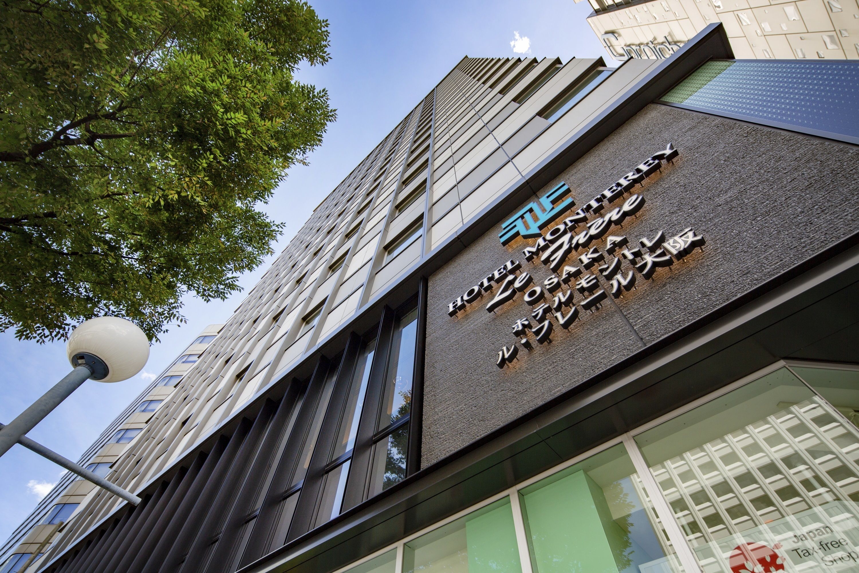 Placa de hotel com o nome 'Hotel Monte Carlo' e a inscrição 'Japan Tax-free Shopping'.