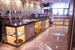 Buffet montado com várias estações de serviço, parede de tijolos com vegetação e piso limpo revestido de azulejos.