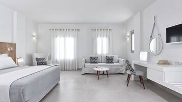 Quarto de hotel moderno com cama, sofá, escrivaninha e cadeira.