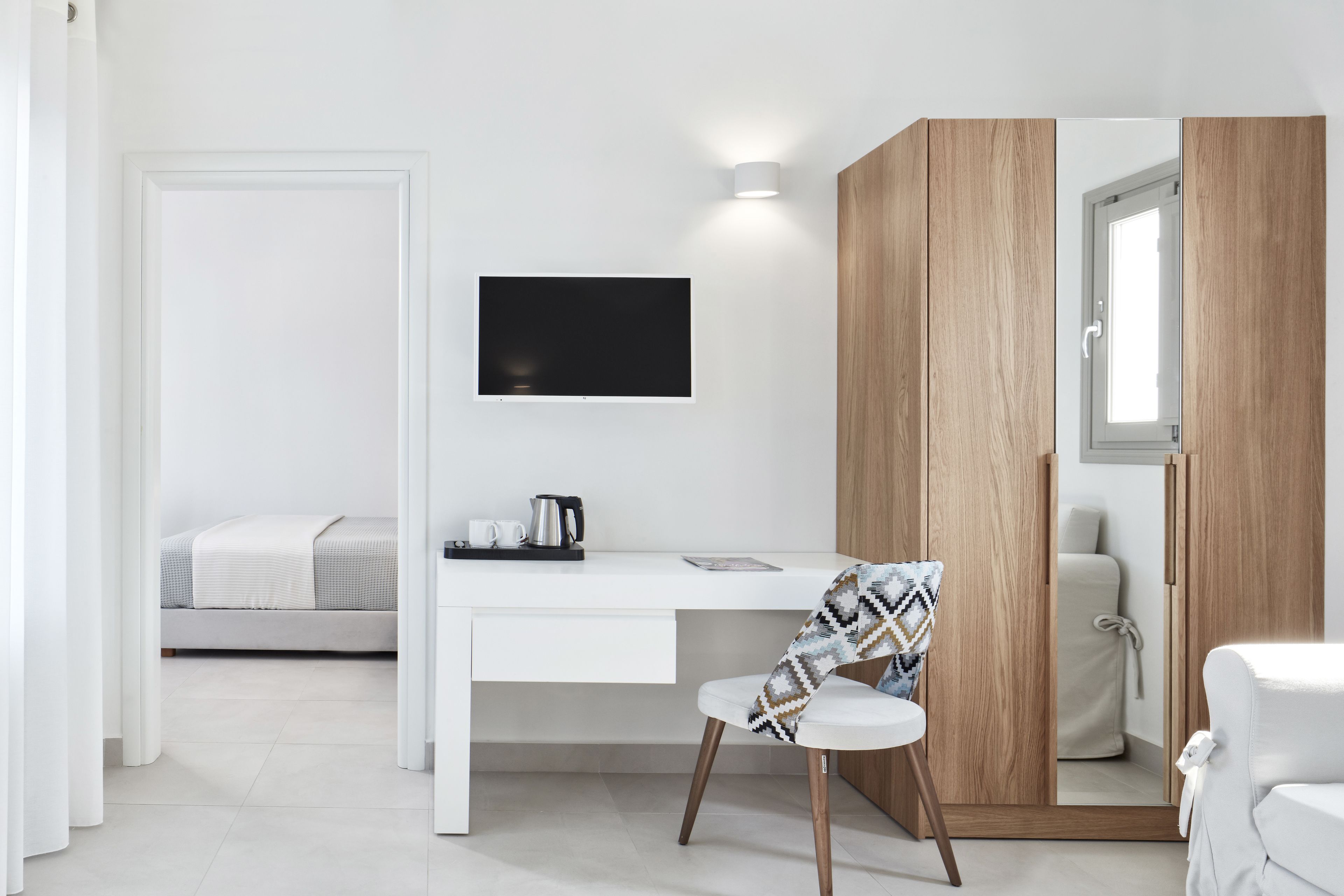 Quarto moderno e minimalista com uma escrivaninha branca, uma cadeira, uma cama e um guarda-roupa.