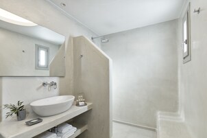 Uma casa de banho moderna com uma grande pia branca, um espelho e zona de duche.