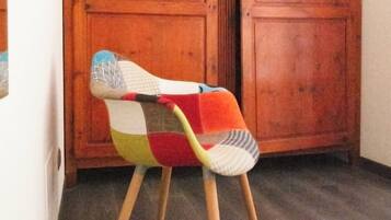 Uma cadeira com um design colorido e de patchwork em um quarto com armários de madeira e piso de madeira escura.