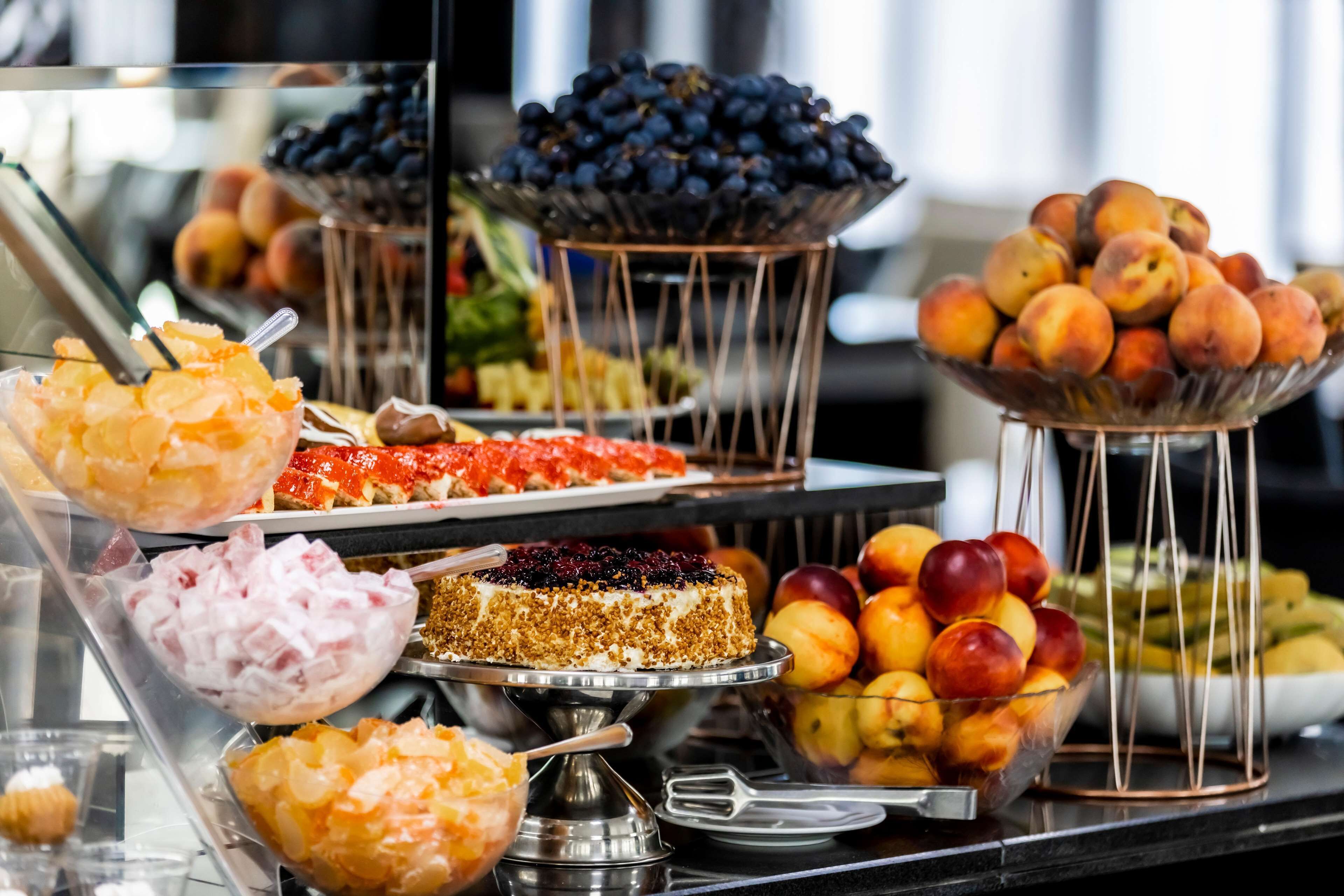 Buffet com diversas opções de comida, incluindo frutas, sobremesas e um bolo.