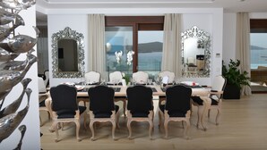 Uma sala de jantar com uma mesa grande, seis cadeiras e dois espelhos elaborados.