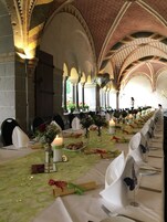 Uma longa mesa de banquete com velas, flores e toalha de mesa verde.
