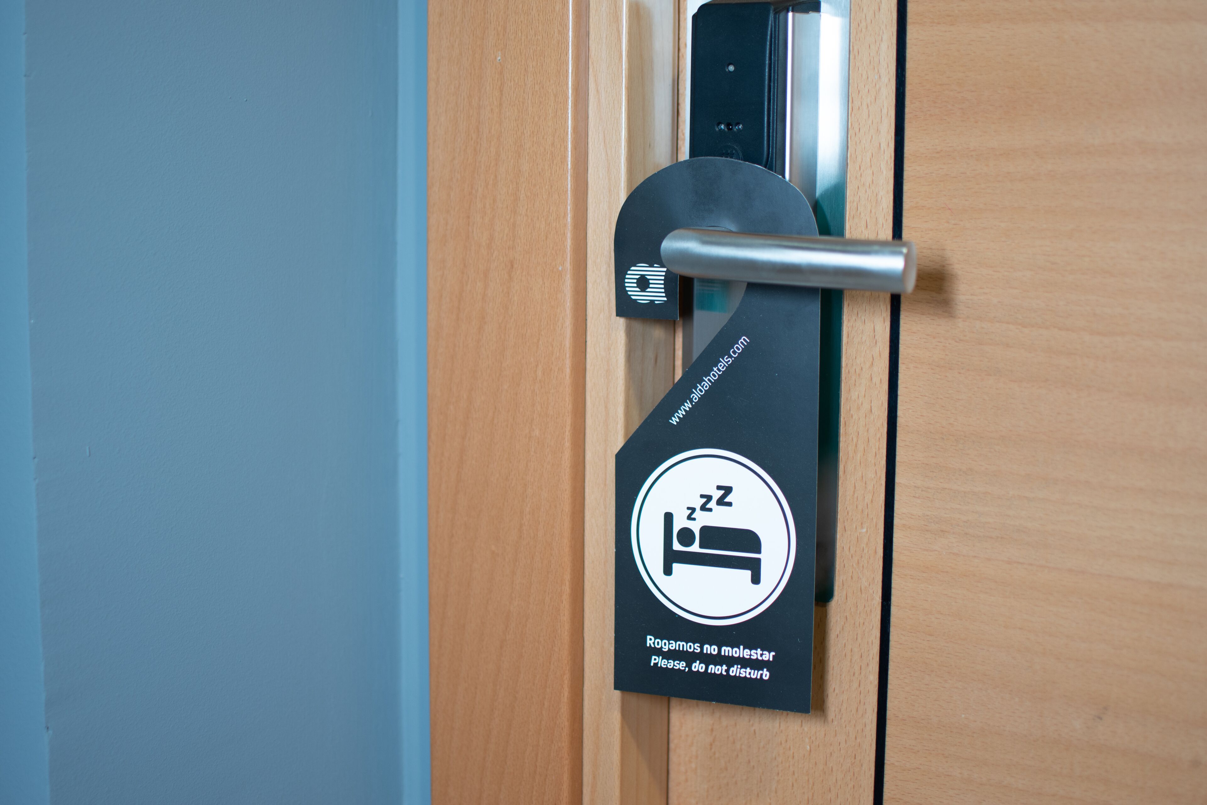 Uma porta com uma placa que diz 'Rogamos não incomodar'.