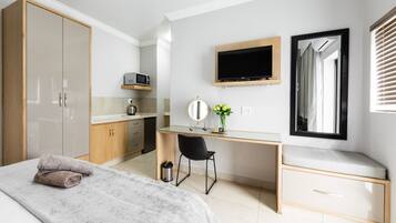 Um quarto moderno com uma cama, uma escrivaninha, uma cadeira, uma televisão e um guarda-roupa.