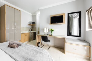 Um quarto moderno com uma cama, uma escrivaninha, uma cadeira, uma televisão e um guarda-roupa.