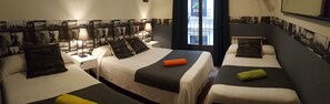 Quarto de hotel com duas camas, uma mesa de cabeceira, uma luminária e vista para a cidade pela janela.