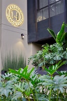 Placa de hotel com o nome 'CATORCE URBAN HOTEL' e fachada de prédio moderna com grandes janelas e jardim vertical.