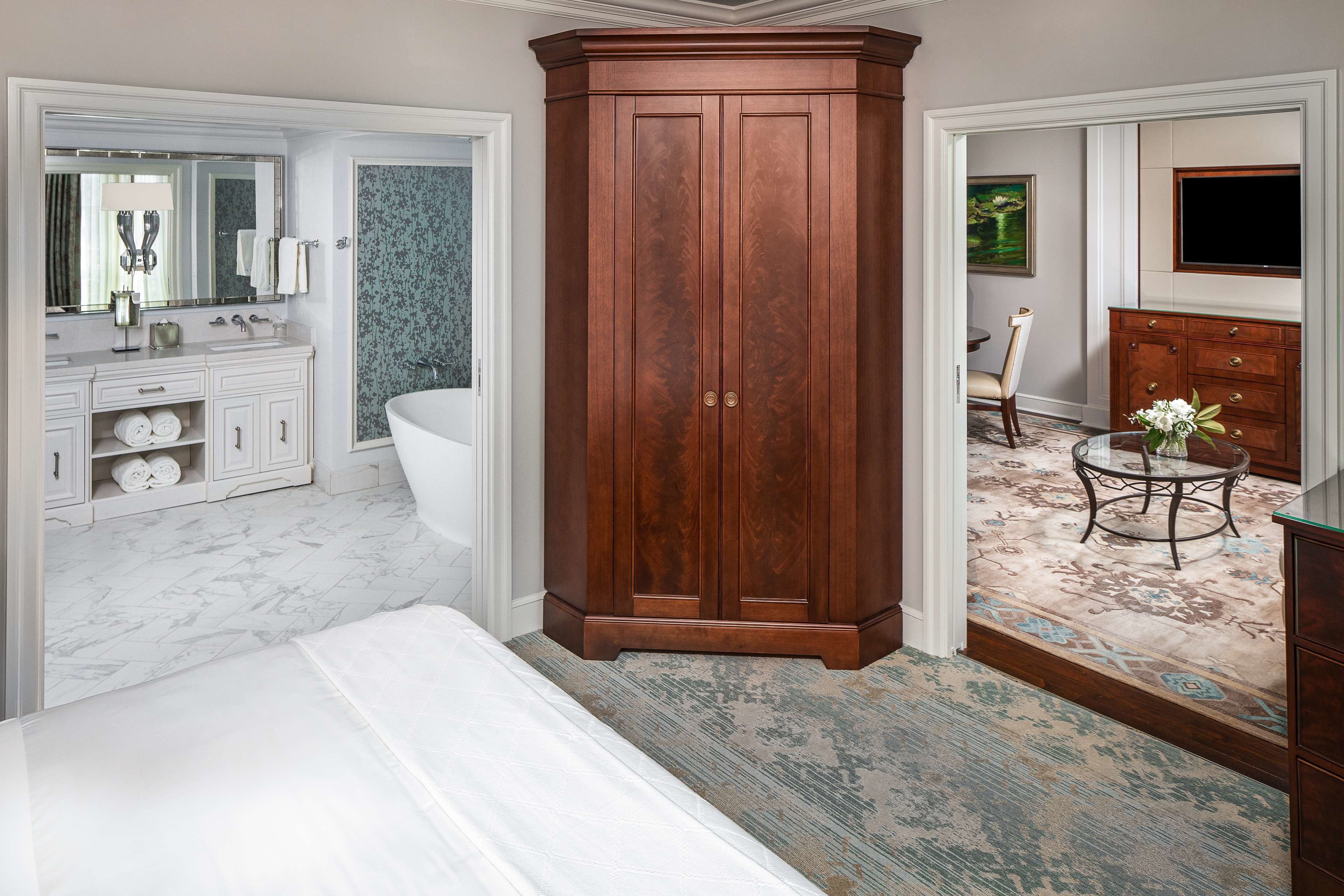 Quarto com guarda-roupa espaçoso, cama e banheiro com piso de mármore.