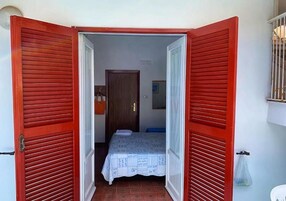 Um quarto com cama, porta e uma pequena janela.