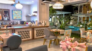 Uma área de bar moderna com vista para a piscina, com banquetas, mesas e diversos equipamentos de bar.