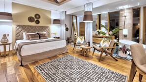 Quarto moderno com cama grande, ventilador de teto e área de estar com mesa de centro e cadeiras.