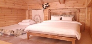 Quarto de cabana de madeira com cama e um pequeno espaço para sentar.