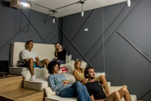 Um grupo de pessoas sentadas num sofá numa sala com design moderno, incluindo um padrão geométrico na parede e um projetor instalado no teto.