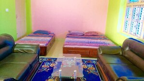 Quarto com duas camas, um sofá e uma mesa.