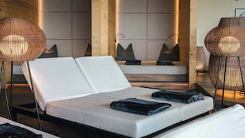 Quarto de hotel moderno com um sofá-cama branco, duas grandes luminárias de chão trançadas e uma cabeceira em tons neutros.