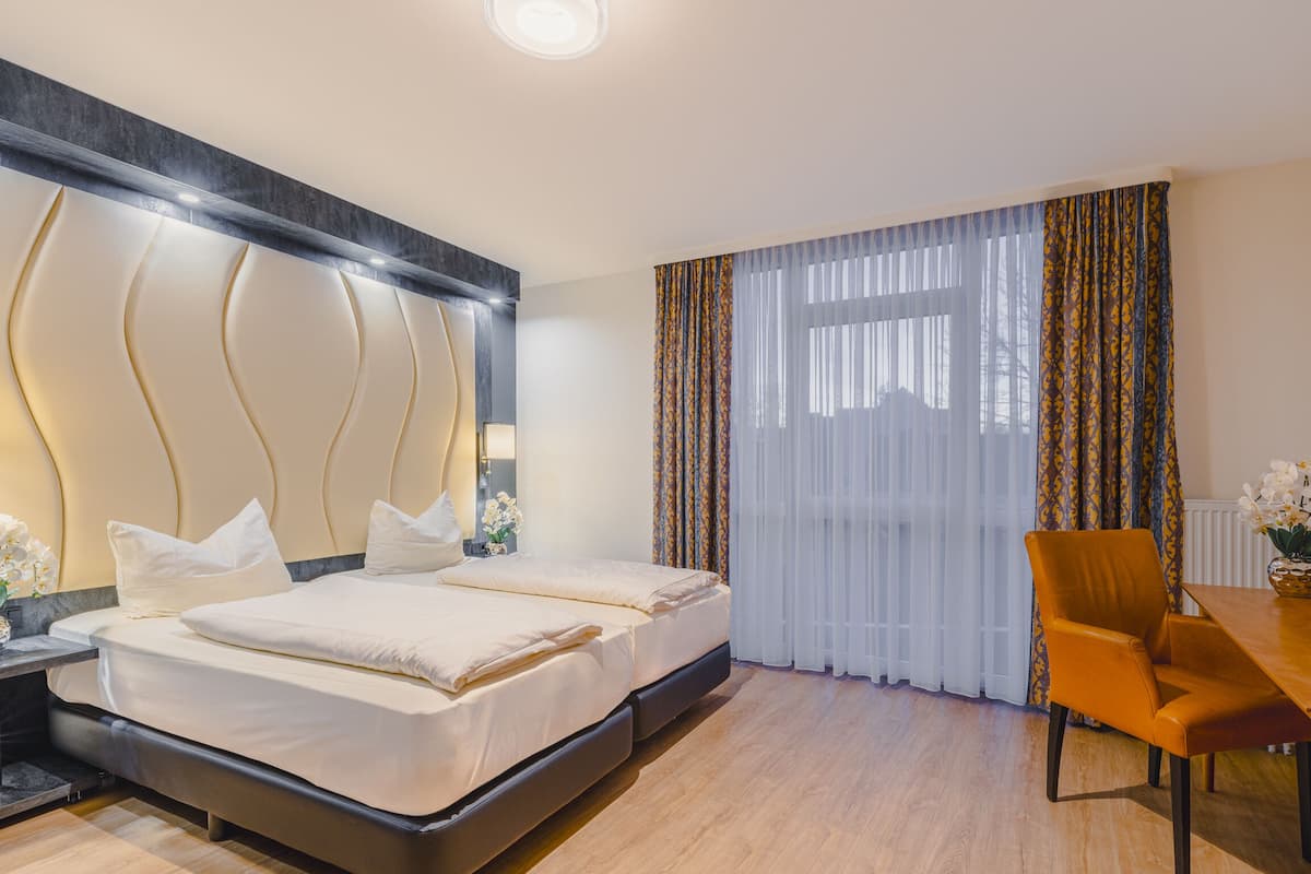 Quarto de hotel moderno com uma cama grande, uma mesa e uma cadeira.