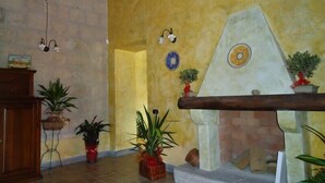 Quarto com lareira, piso de azulejos e vários vasos de plantas.