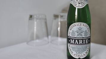 Uma garrafa de cerveja Marie-Stella-Mars com rótulo, colocada sobre uma mesa com dois copos vazios.