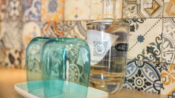 Uma garrafa de álcool da marca Hotel Serra d'Aire e um recipiente de vidro sobre uma mesa com azulejos.