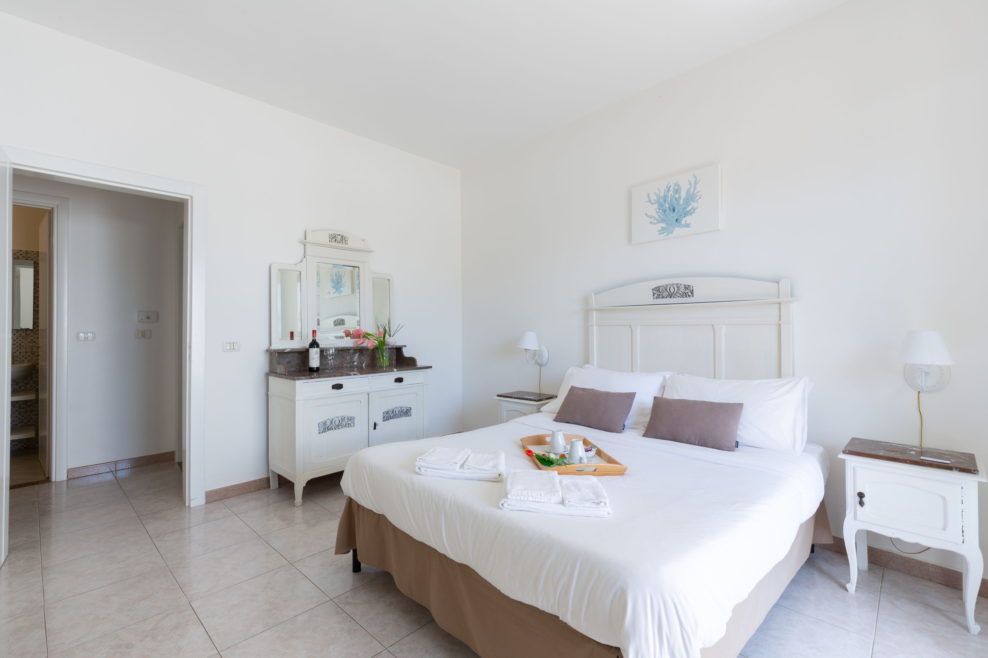Um quarto espaçoso com uma cama grande, penteadeira, mesa de cabeceira e espelho.