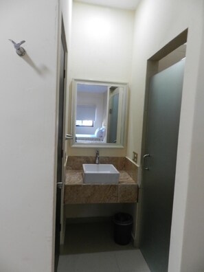 Uma casa de banho pequena com uma sanita branca, um espelho em cima e uma porta à direita.