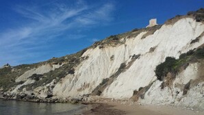 Paisagem costeira com um castelo em um penhasco, uma praia e um céu claro.