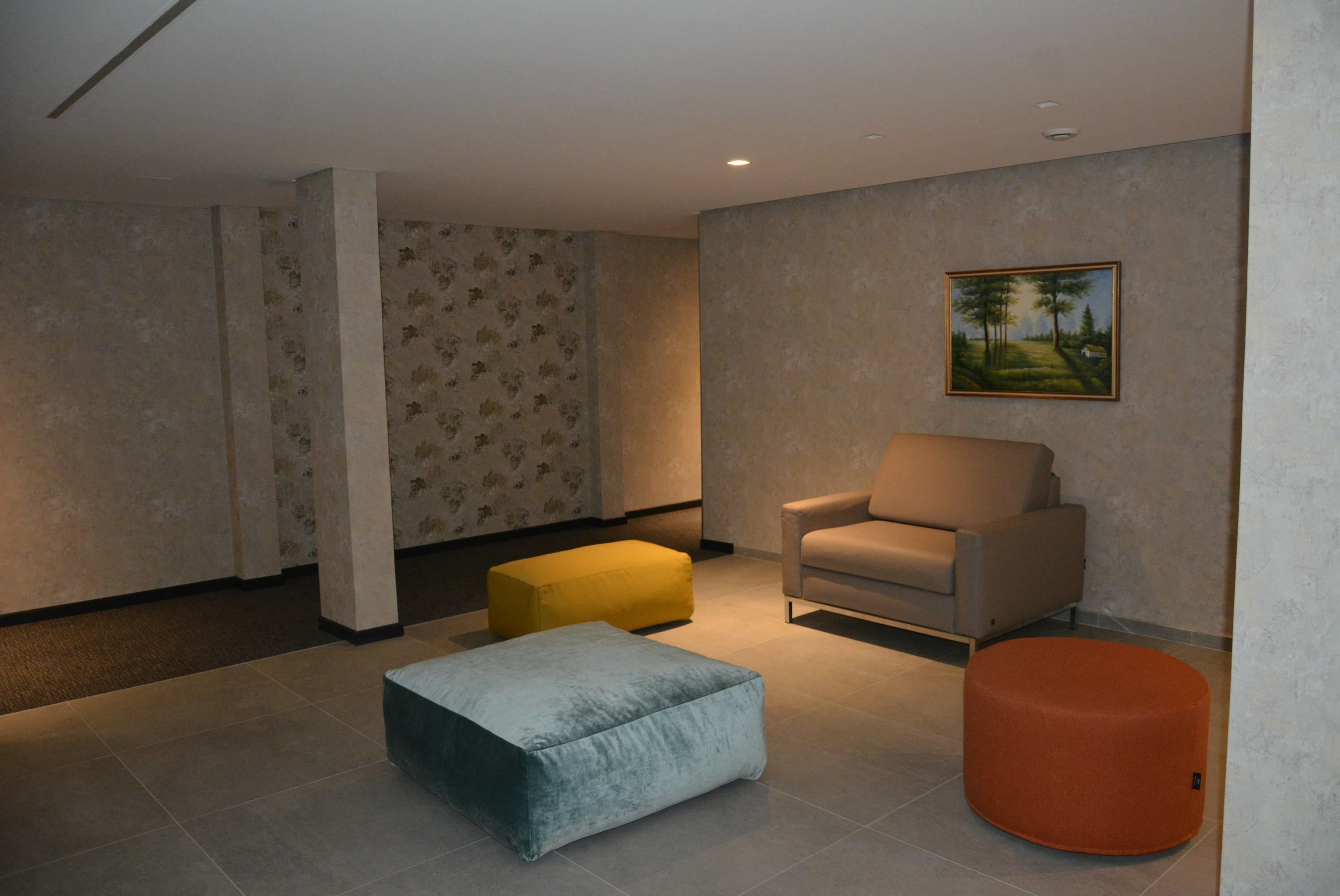 Uma sala de estar moderna com sofá, pufes e um quadro na parede.