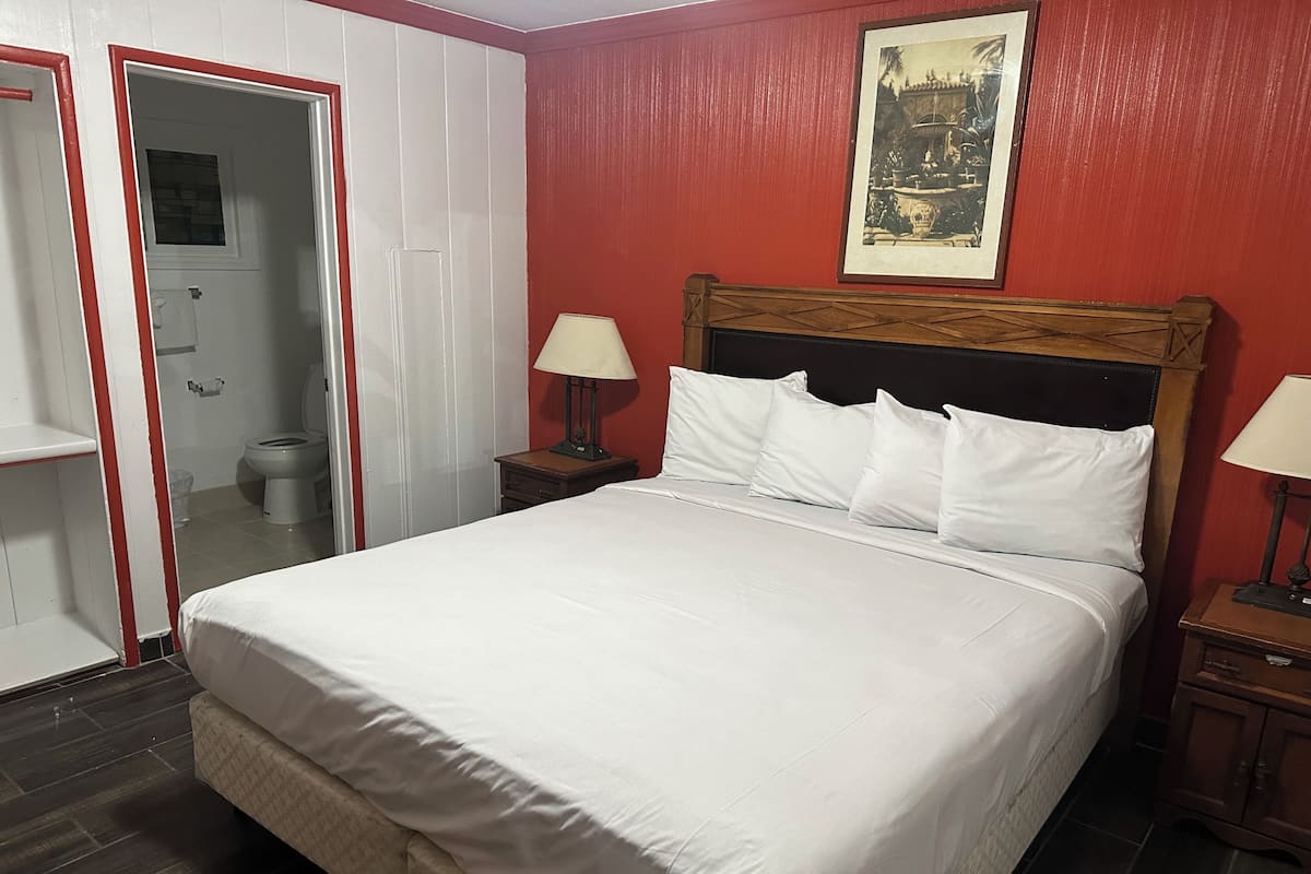 Uma cama bem arrumada com lençóis brancos, uma cabeceira de madeira e duas luminárias de cabeceira.