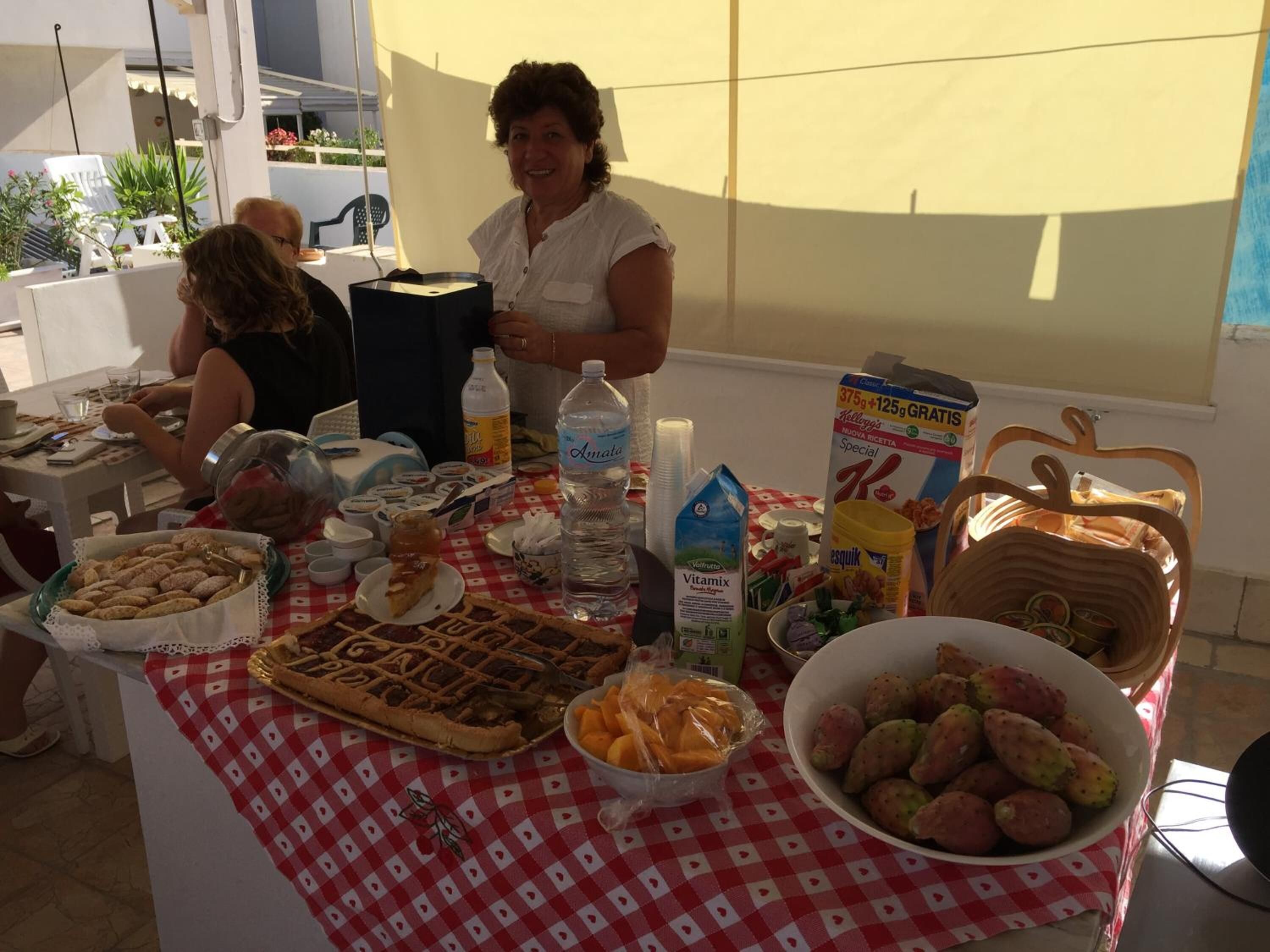 Uma mesa com diversos alimentos e bebidas, incluindo um waffle, uma tigela de frutas e uma caixa de cereal.