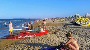 Uma praia com pessoas, barcos e uma torre salva-vidas.