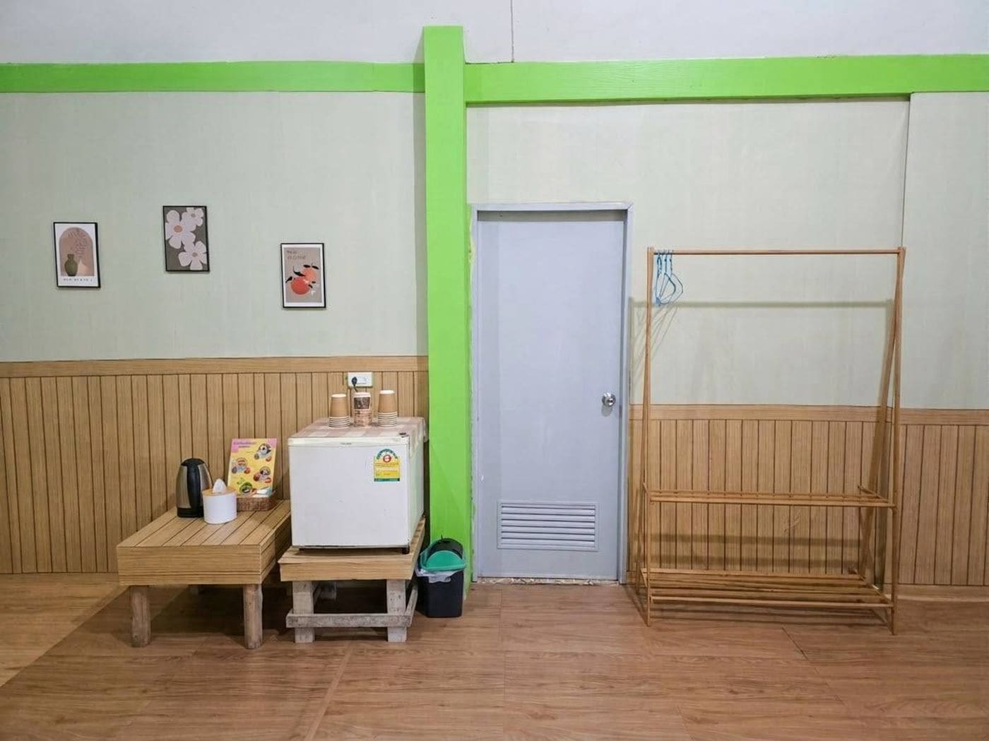 Quarto com uma mesa de madeira, um frigorífico, uma porta e uma estante.