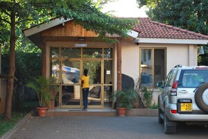 Uma área de recepção com fachada de madeira, entrada de vidro e um SUV estacionado.