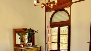 Quarto com cama grande, penteadeira de madeira e uma cadeira.