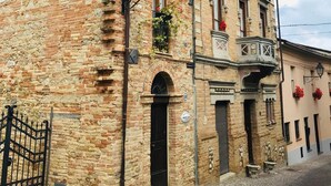 Um edifício histórico com fachada de tijolos, uma varanda com jardineiras e um poste de rua tradicional.