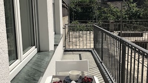 Varanda com uma mesa posta para dois, exibindo uma tigela de cerejas, uma xícara e um pires.