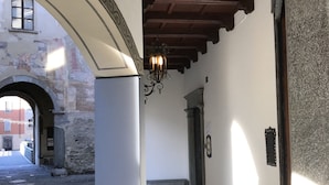 Um pátio de pedra com uma entrada arqueada, um banco e um candelabro.