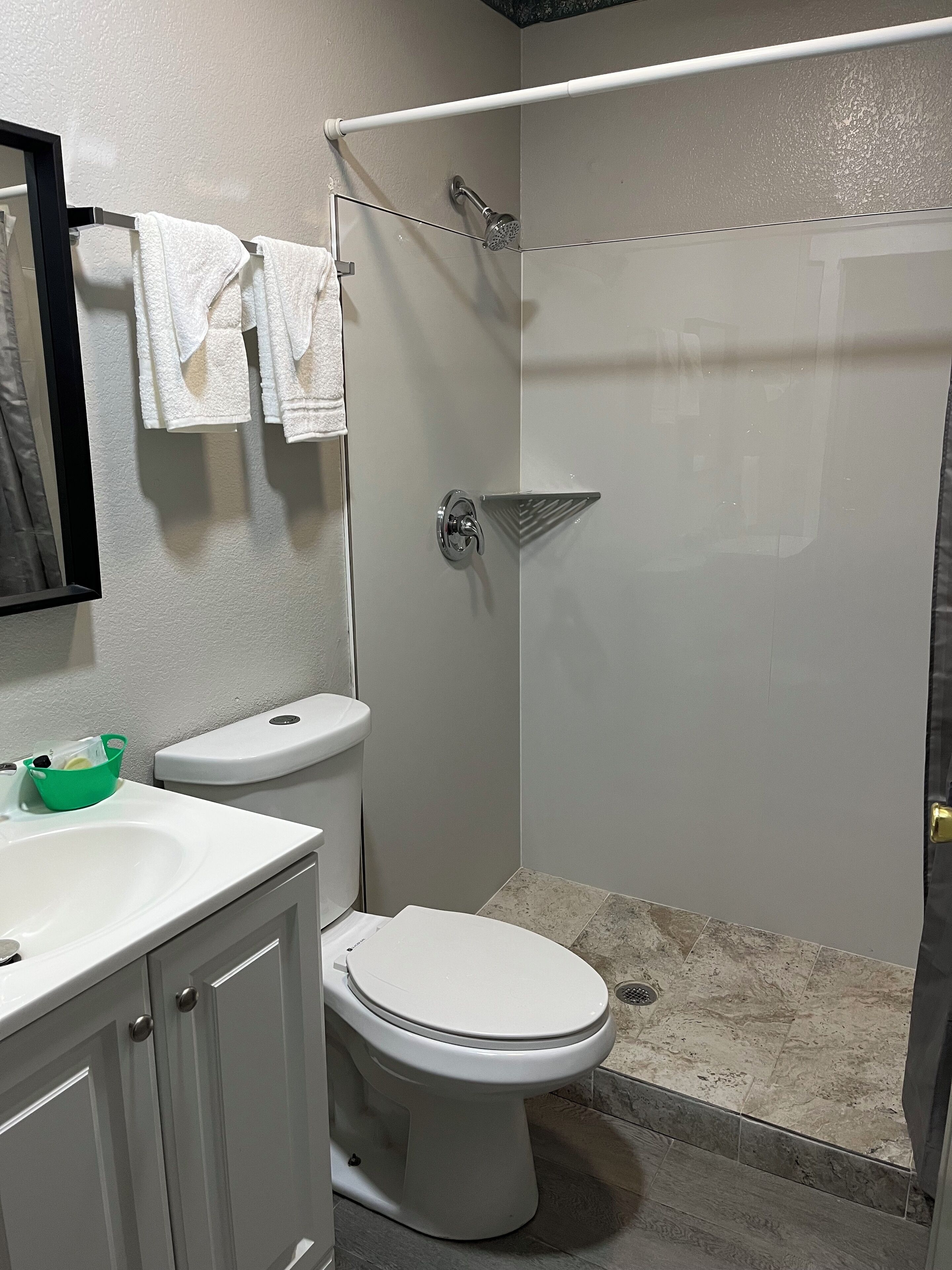 Uma casa de banho moderna com sanita, lavatório e chuveiro.