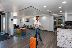 Um saguão de hotel moderno com área de estar, balcão de recepção e sinalização de saída visível.