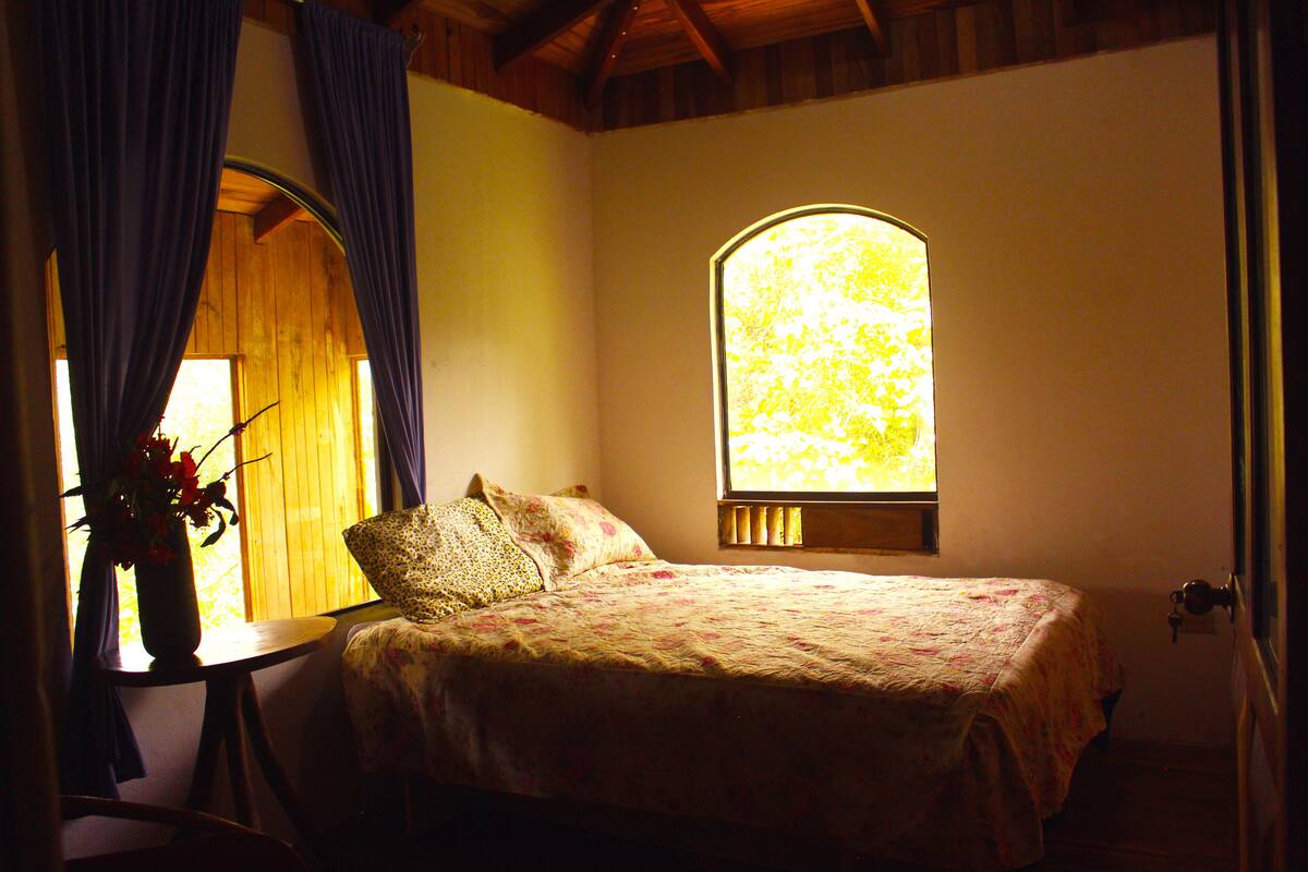 Quarto com cama, janela e cortinas.