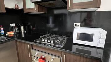 Uma cozinha com armários de madeira escura, fogão de aço inoxidável, micro-ondas e painel de azulejos.