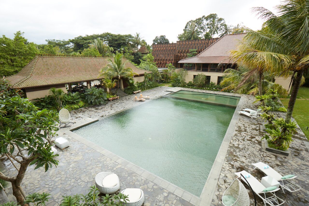 Área de piscina com espreguiçadeiras e uma pequena cascata.